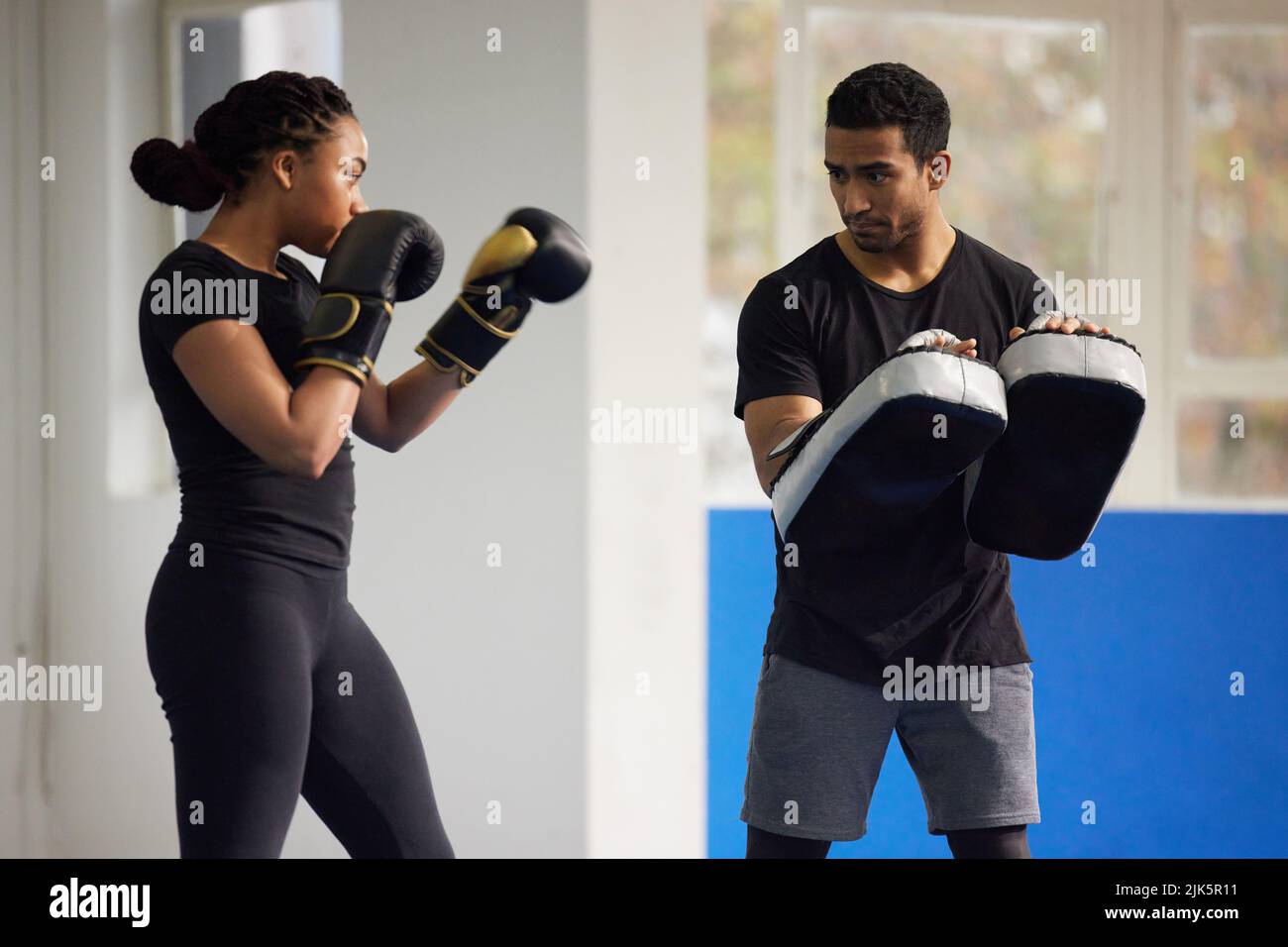 Coaching her through the challenge. a young woman practicing boxing ...