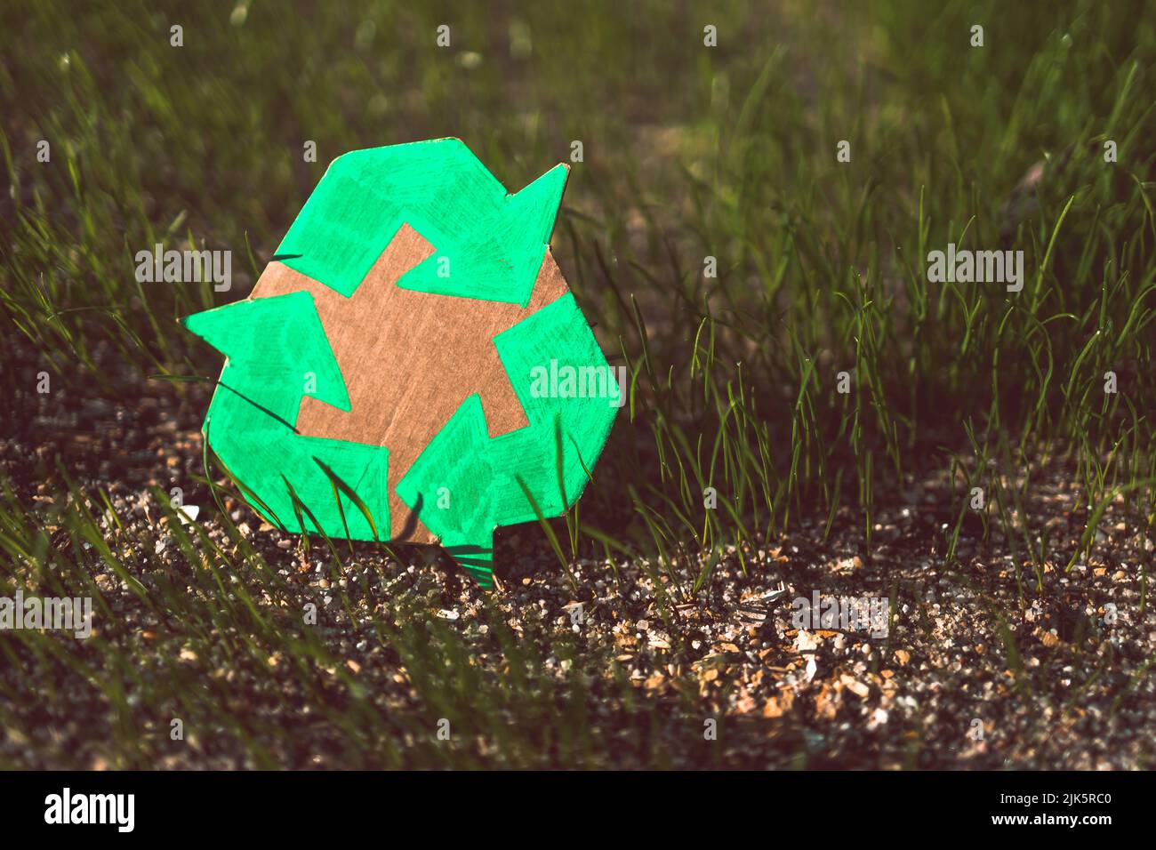 recycle sign hand drawn on cardboard over green grass under the ...