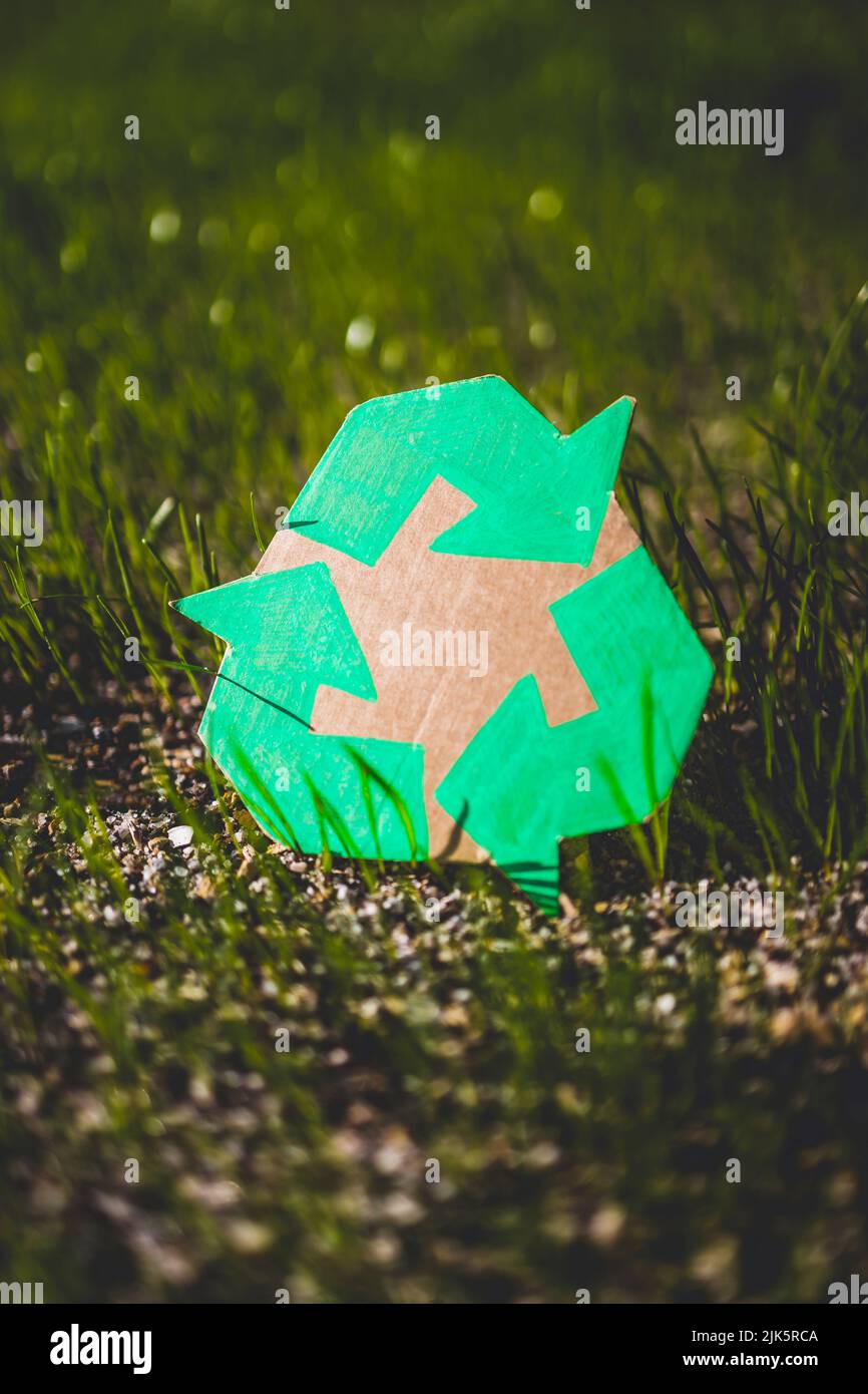 recycle sign hand drawn on cardboard over green grass under the ...
