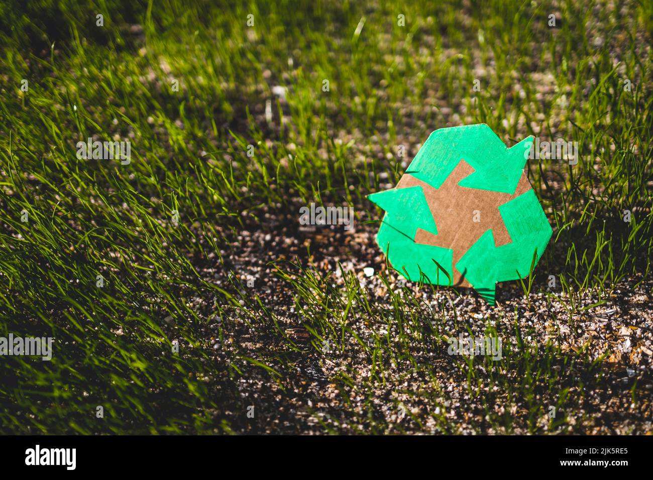 recycle sign hand drawn on cardboard over green grass under the ...