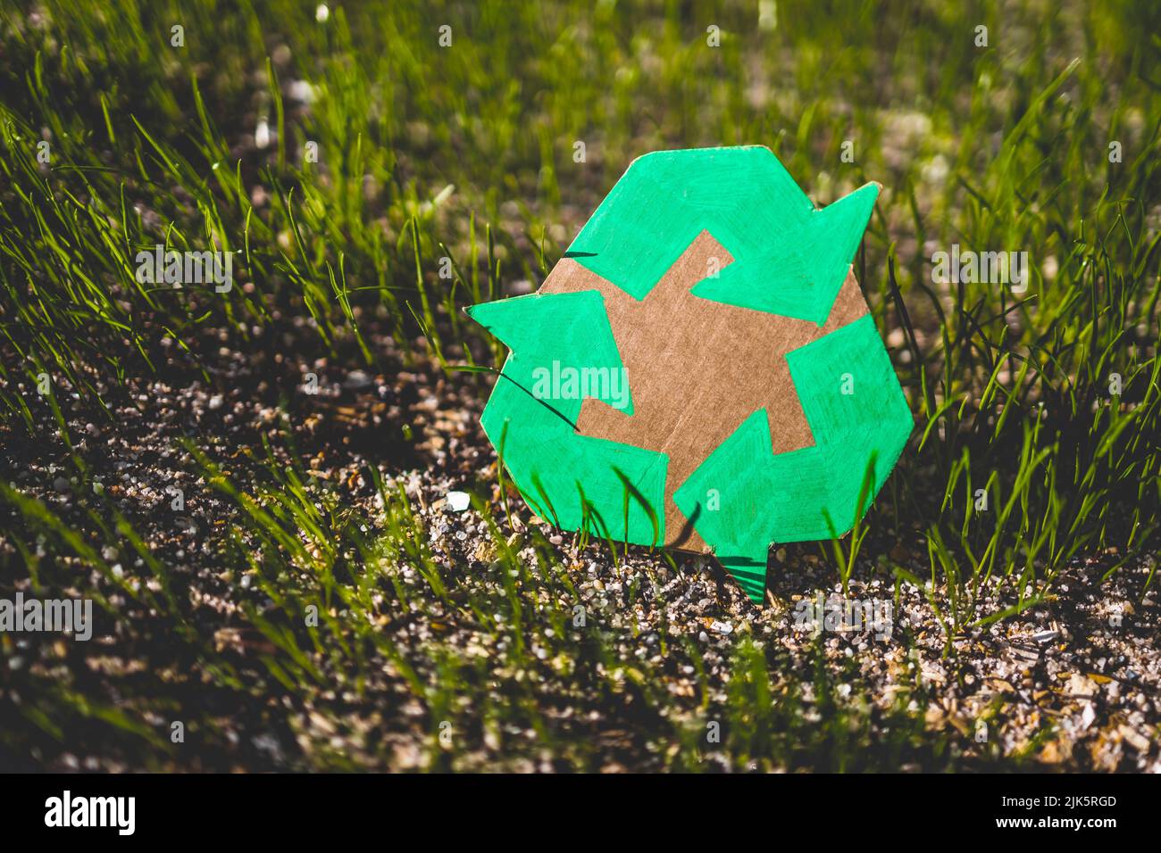 recycle sign hand drawn on cardboard over green grass under the ...