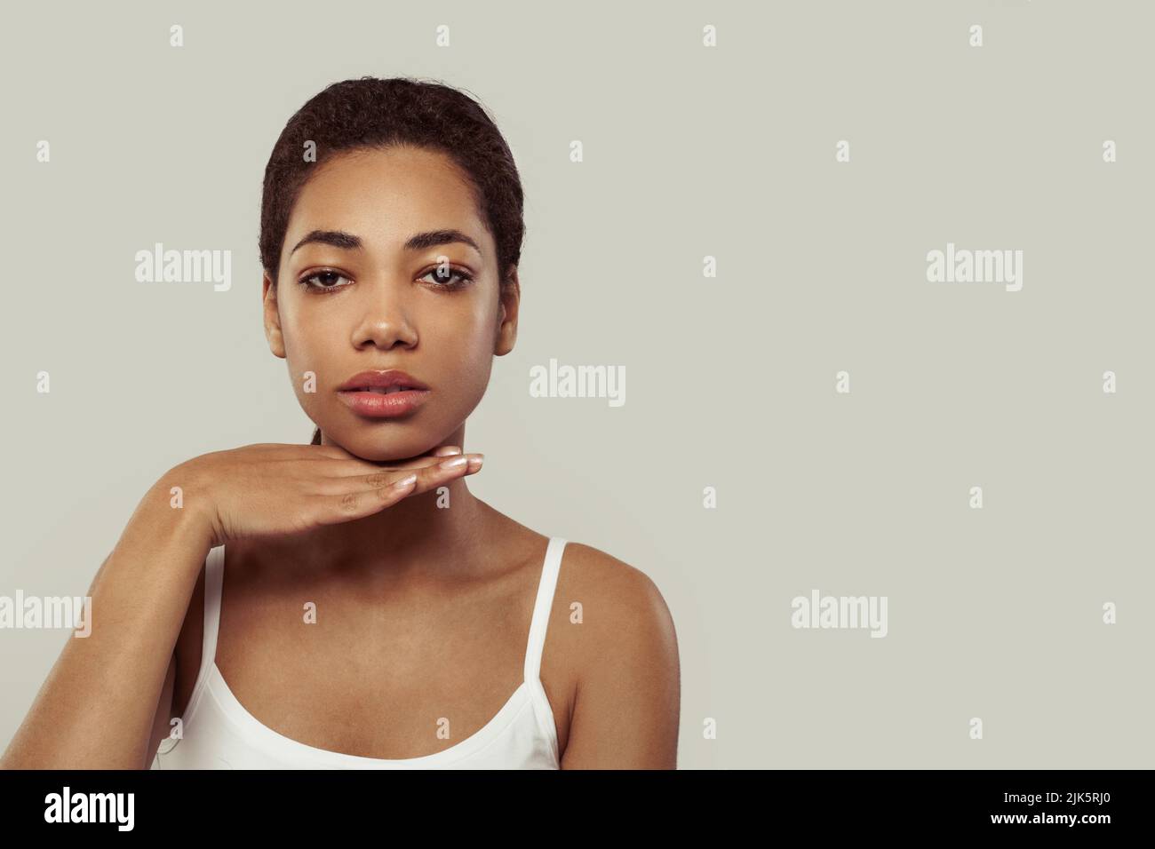 Attractive young model with shiny clean skin touching her chin on white ...