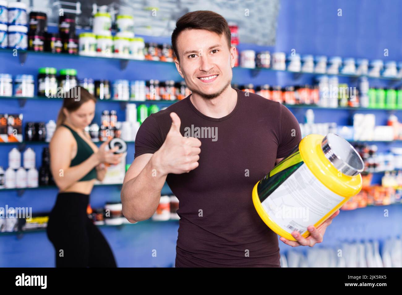 Confident athletic guy posing in shop of sports nutritional supplements ...