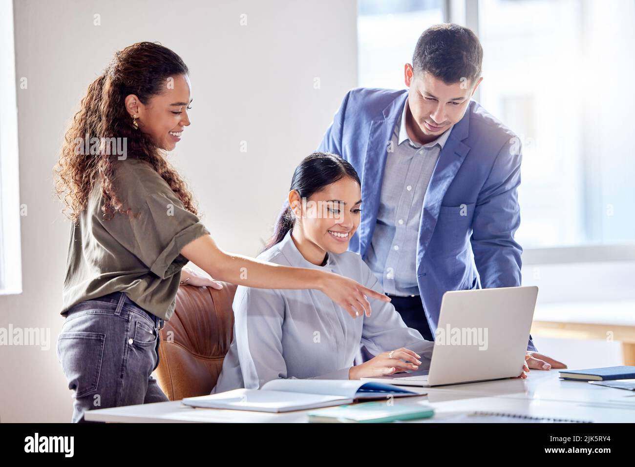 Whats that. a group of colleagues using a laptop in an office at work ...