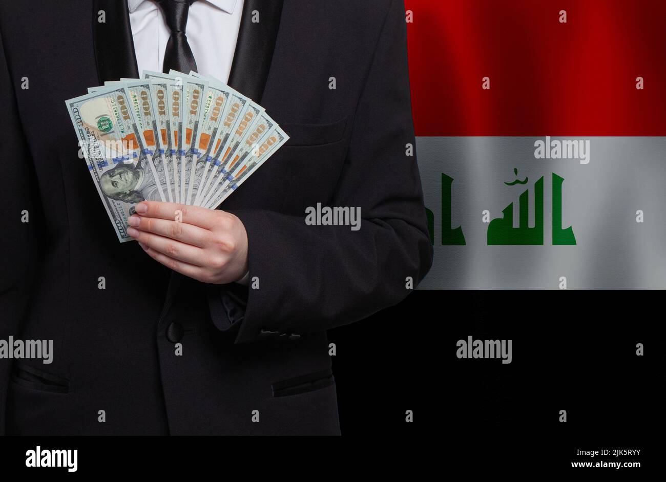 Iraqi business man hand showing US 100 dollar bills against flag of ...