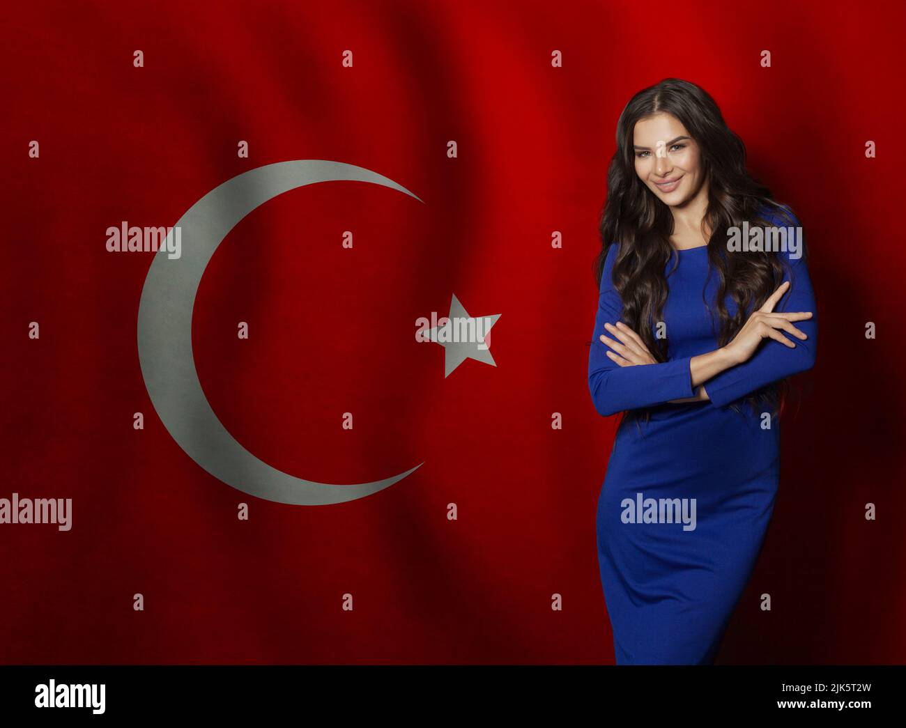 Cheerful young woman in blue dress smiling against Turkish flag ...