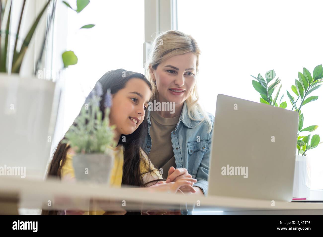 Beautiful mother and child looks at laptop screen spend time in kitchen ...