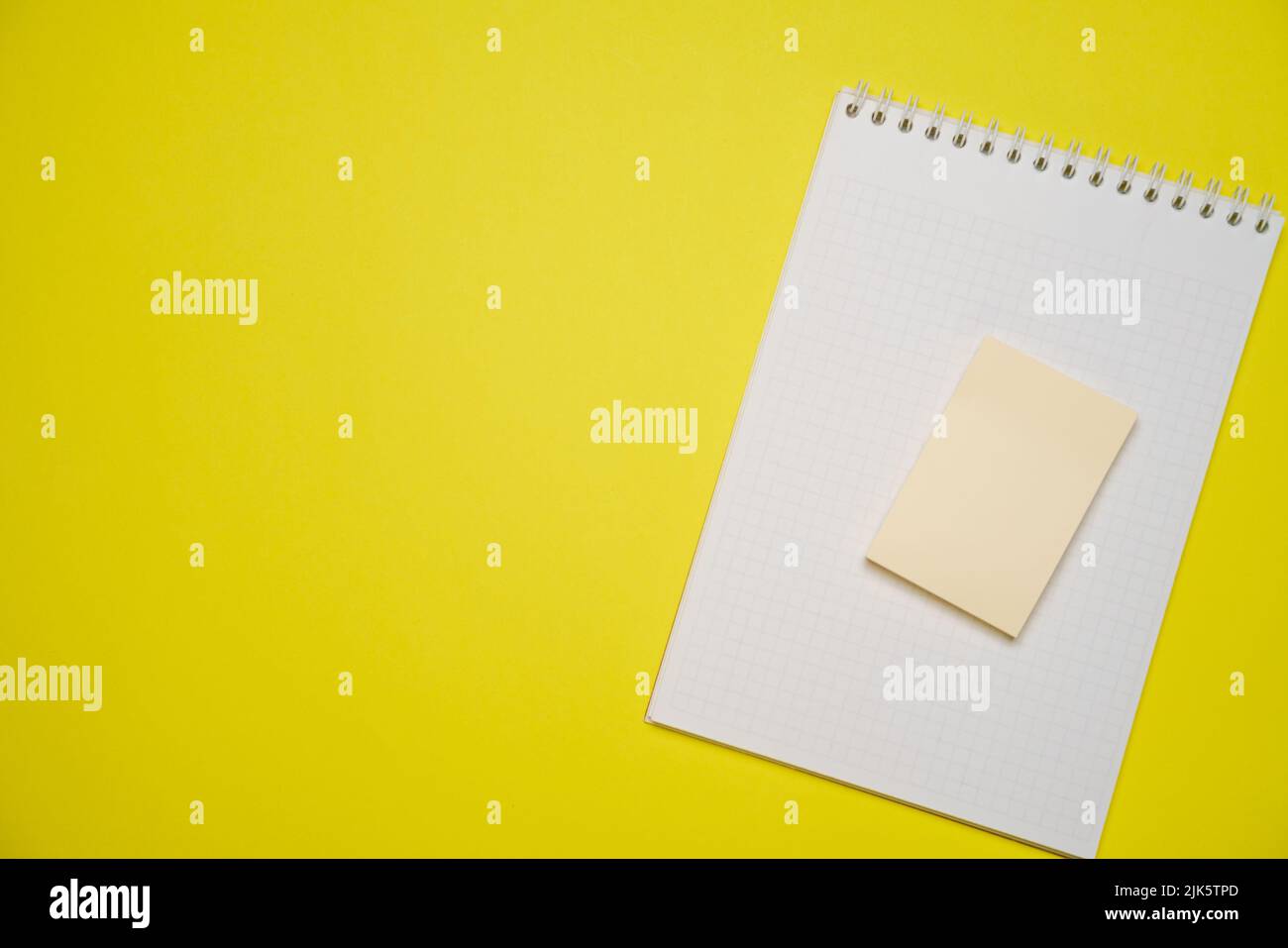 Open blank white notepad on a spiral and stickers on a yellow ...