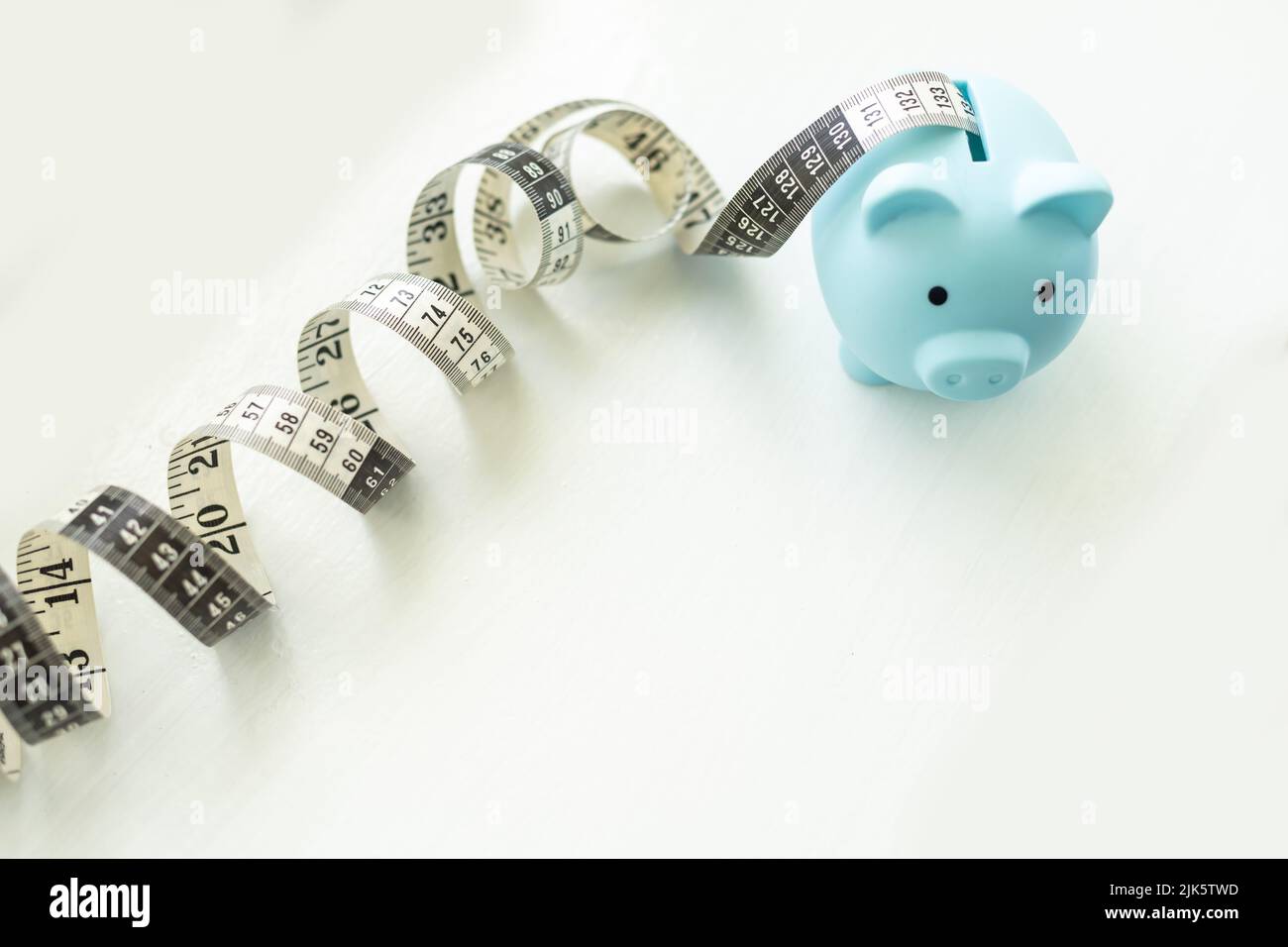 Piggy bank with measure tape Stock Photo - Alamy