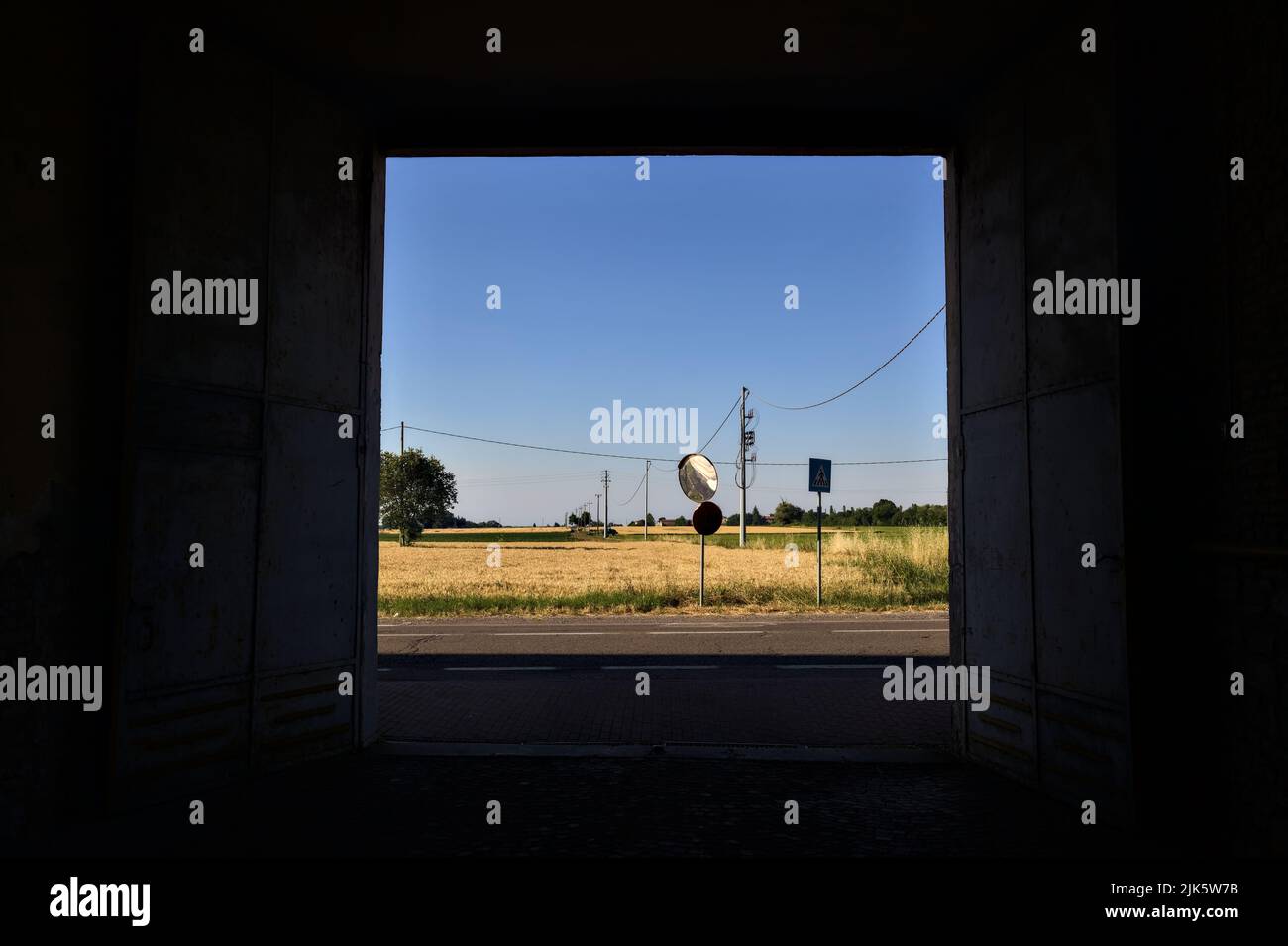 Wheat field on a sunny day seen through an open gate in the shade Stock ...