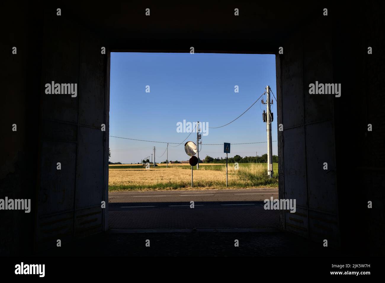 Wheat field on a sunny day seen through an open gate in the shade Stock ...