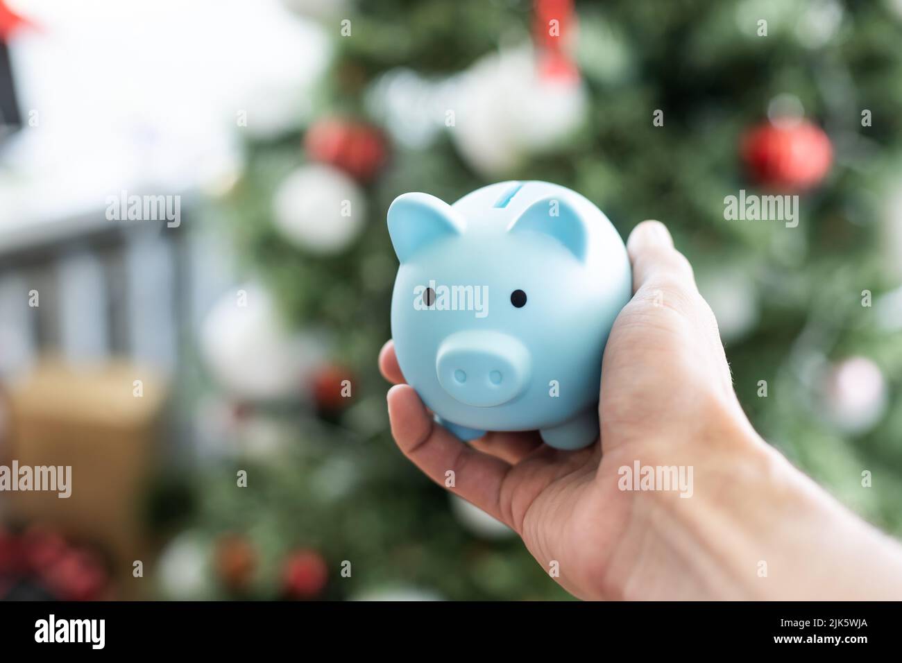 A small ceramic piggy bank with a Christmas tree. In the background of ...