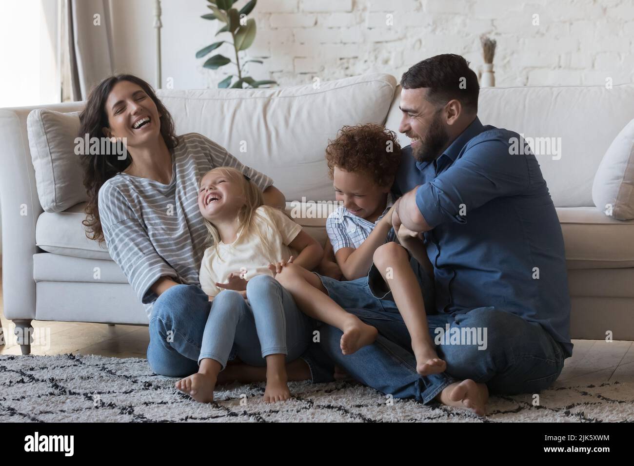 Happy parents cuddling, tickling little children on floor Stock Photo ...