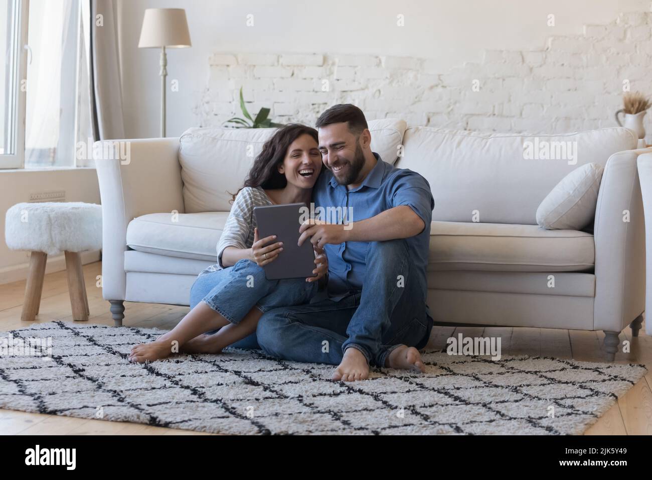 Happy laughing married couple using tablet, sharing digital device ...
