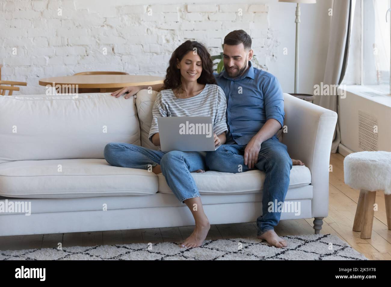 Happy engaged millennial couple in love sitting on couch Stock Photo ...
