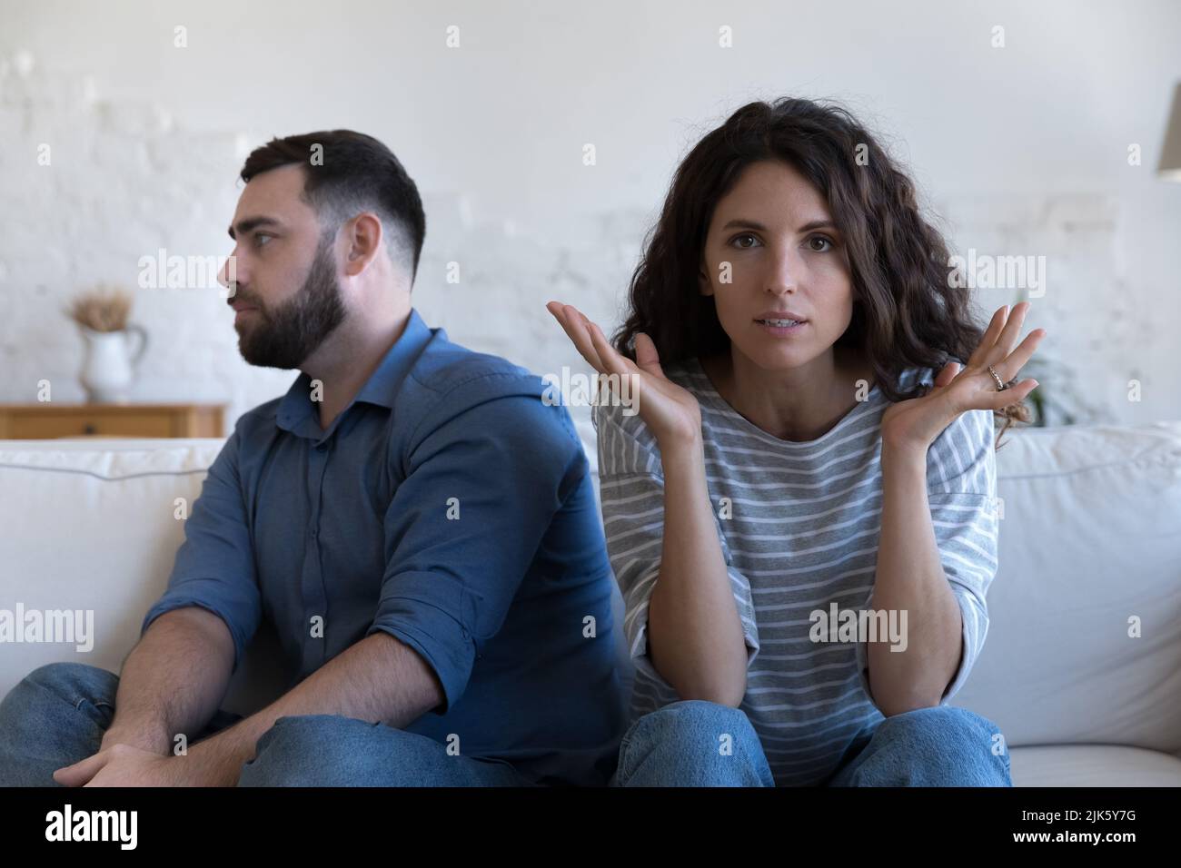 Annoyed Married Couple Sitting On Couch Apart After Conflict Stock