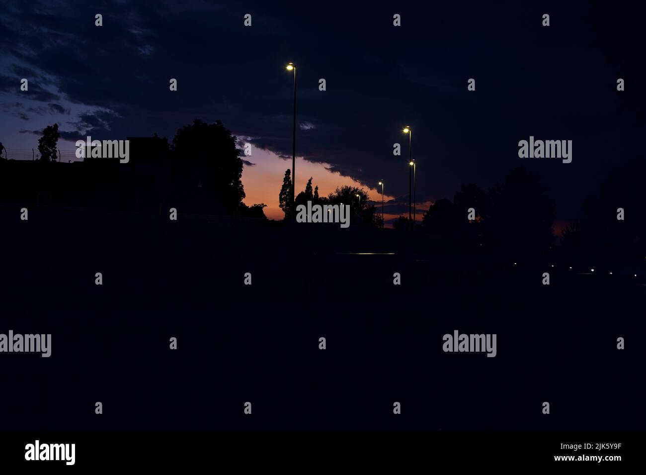 Road with street lights seen from a path at twilight Stock Photo - Alamy