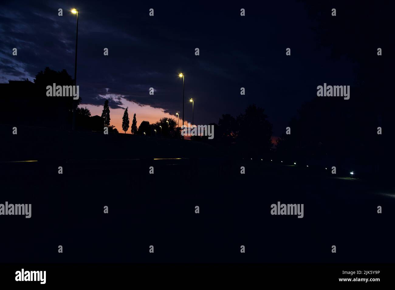 Road with street lights seen from a path at twilight Stock Photo - Alamy
