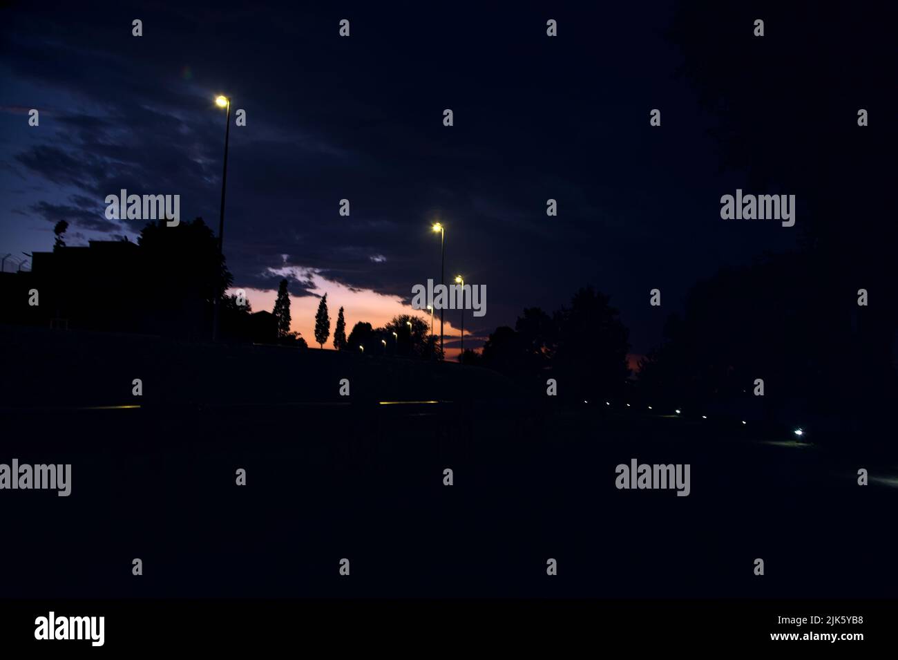Road with street lights seen from a path at twilight Stock Photo - Alamy