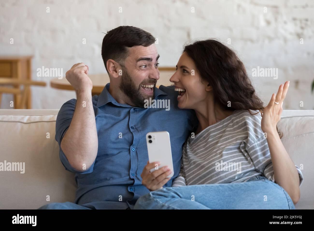 Cheerful excited married couple holding mobile phone Stock Photo - Alamy