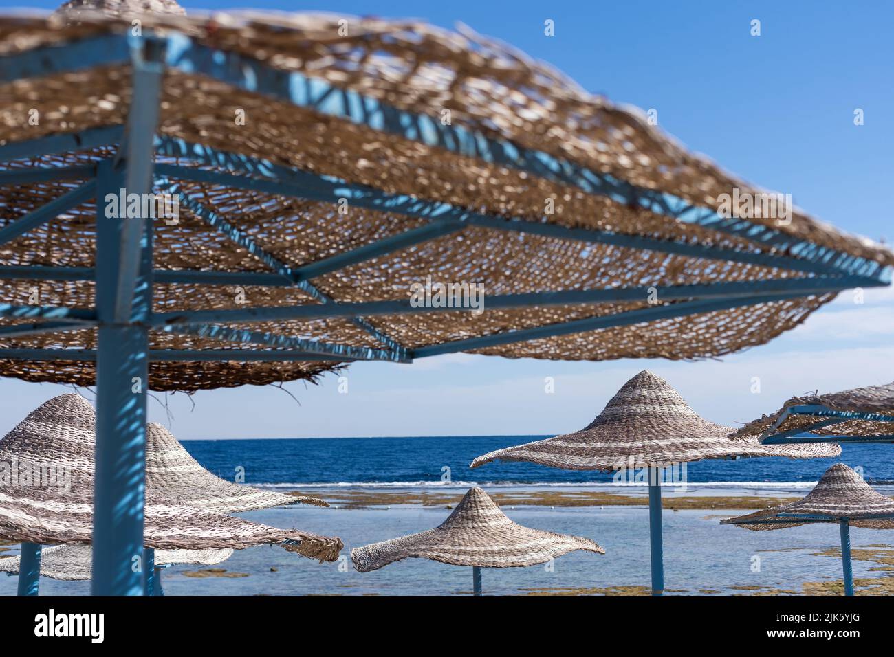 Mediterranean coast with sunbeds and straw sun umbrellas on the sandy ...