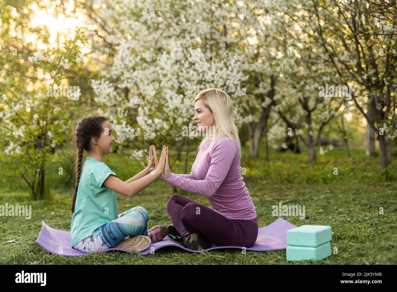 Young sports mother doing physics exercise outdoors in garden near her ...