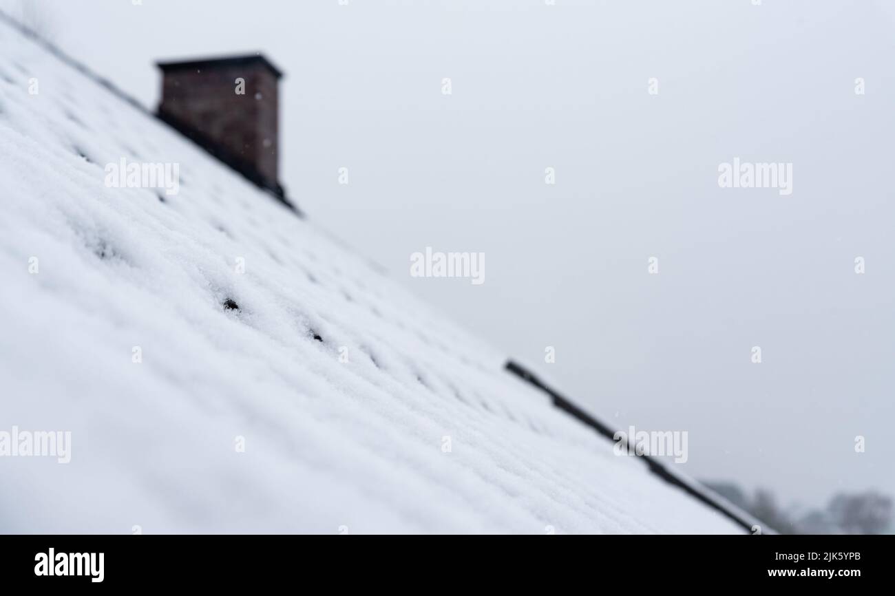 Snow on the roof with a chimney. Brick chimney in winter. House heating ...
