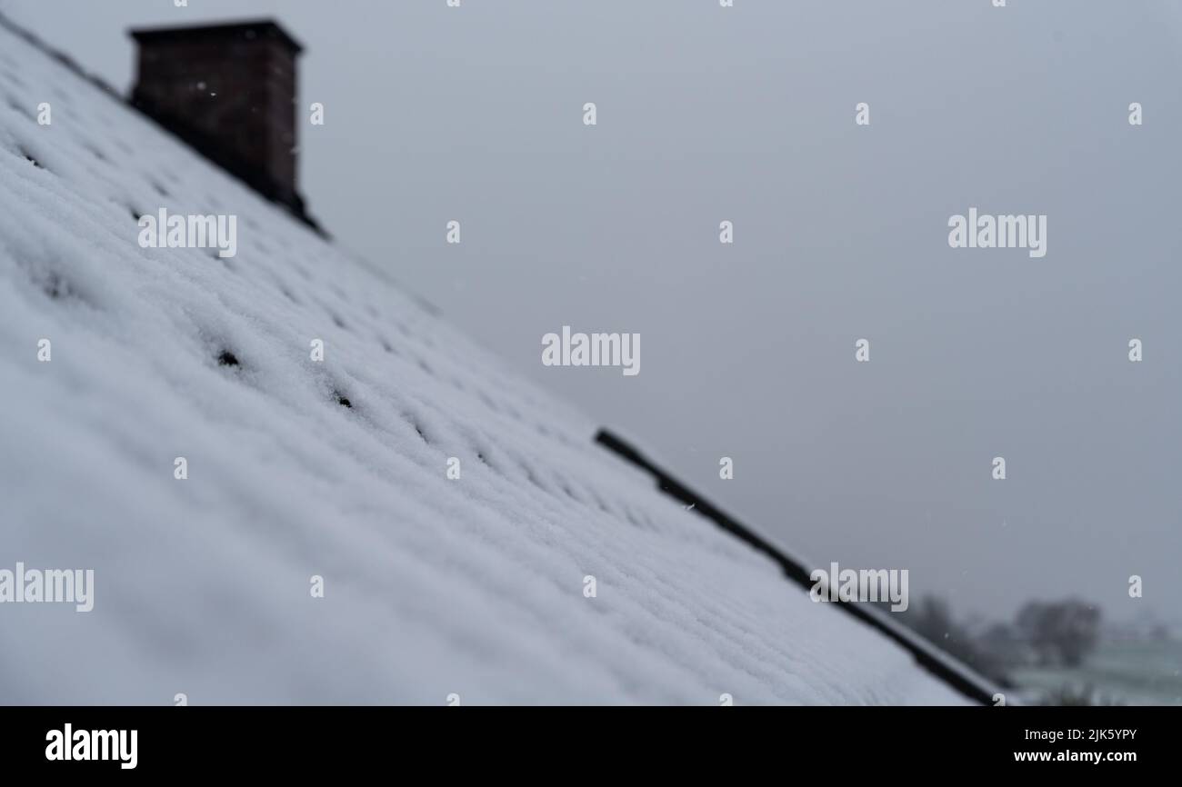 Snow on the roof with a chimney. Brick chimney in winter. House heating ...
