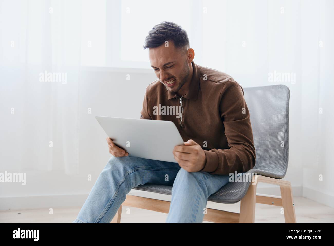 PC software failure concept. Angry aggressive irritated young man hold ...