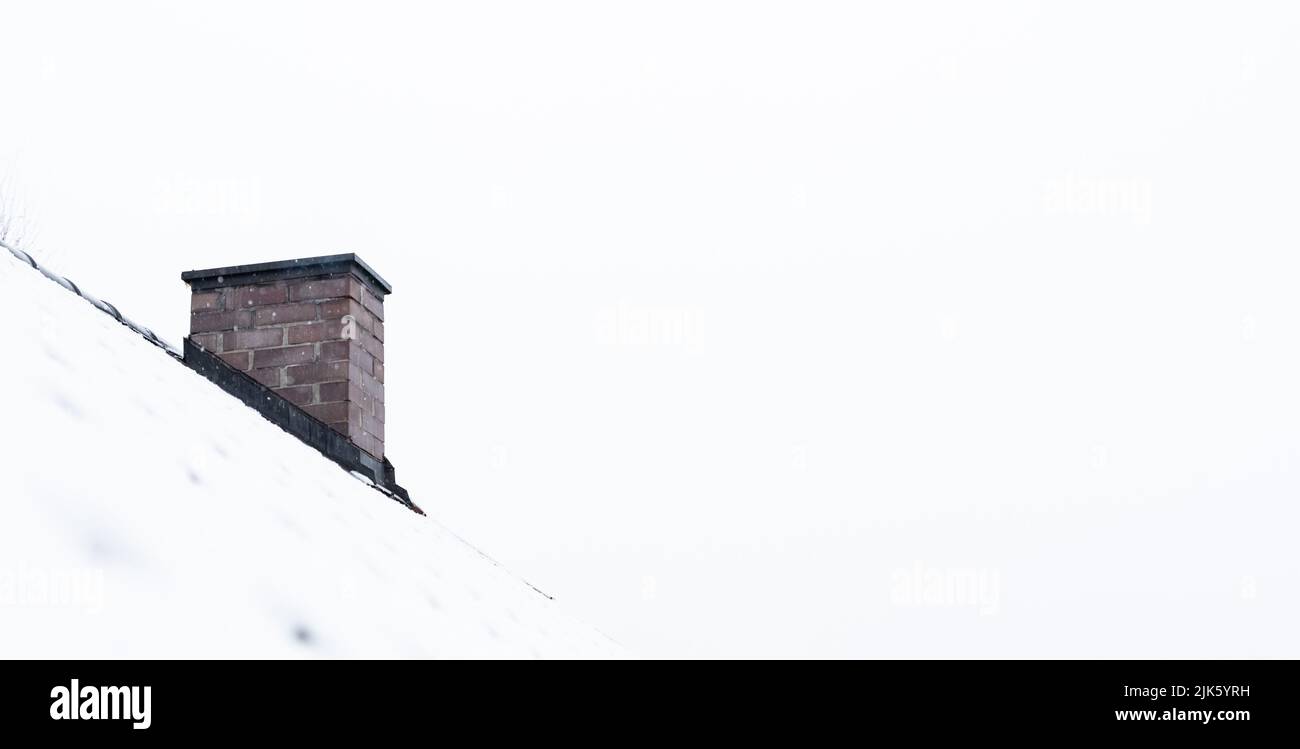 Snow on the roof with a chimney. Brick chimney in winter. House heating ...