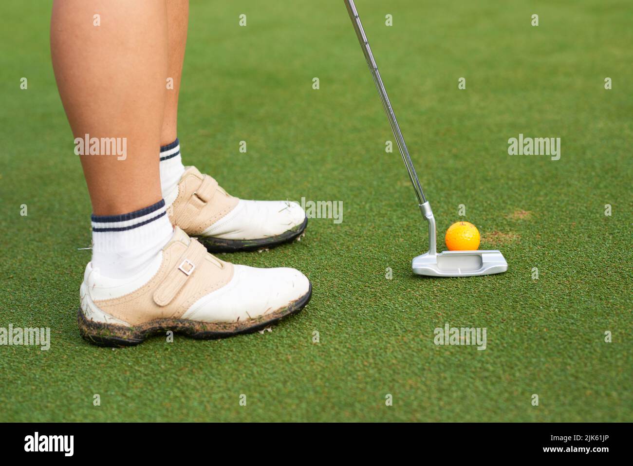 Feet of woman hitting ball into golf hole Stock Photo - Alamy