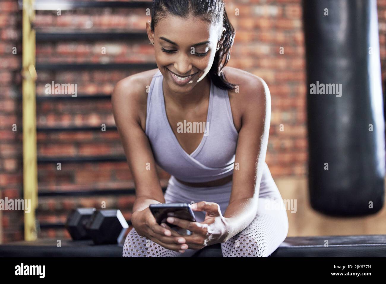 Catching a break between sets. a sporty young woman using a cellphone ...