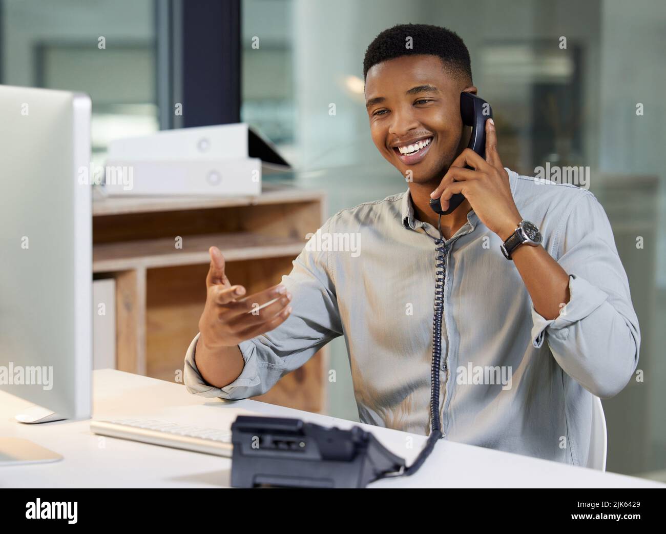 Thats what we love to hear. a young man using a telephone and computer ...