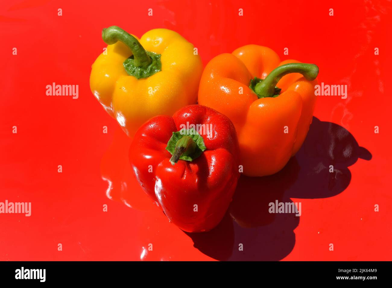 Fresh ripe bell peppers on a red, shiny surface Stock Photo - Alamy