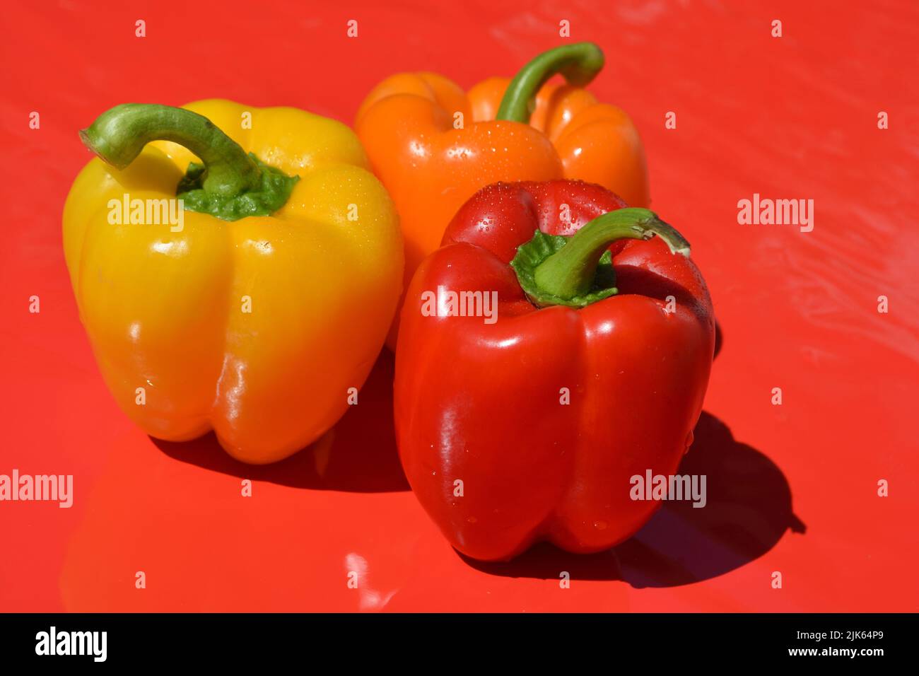 Fresh ripe bell peppers on a red, shiny surface Stock Photo - Alamy
