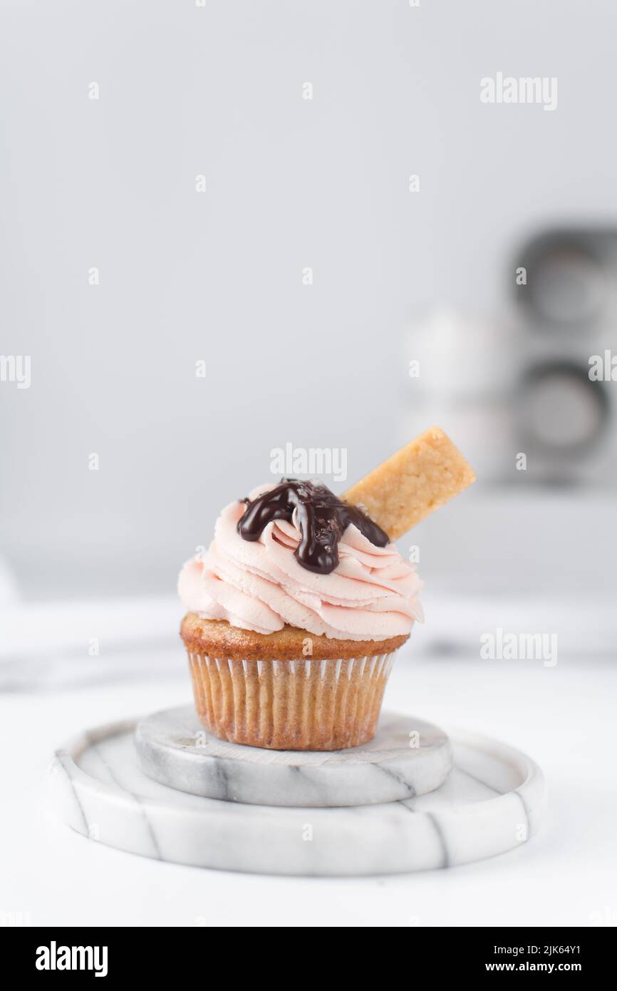 Single vanilla cupcake with a tall swirl of pink frosting, chocolate ...