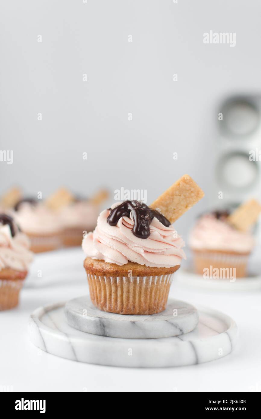 Single vanilla cupcake with a tall swirl of pink frosting, chocolate ...