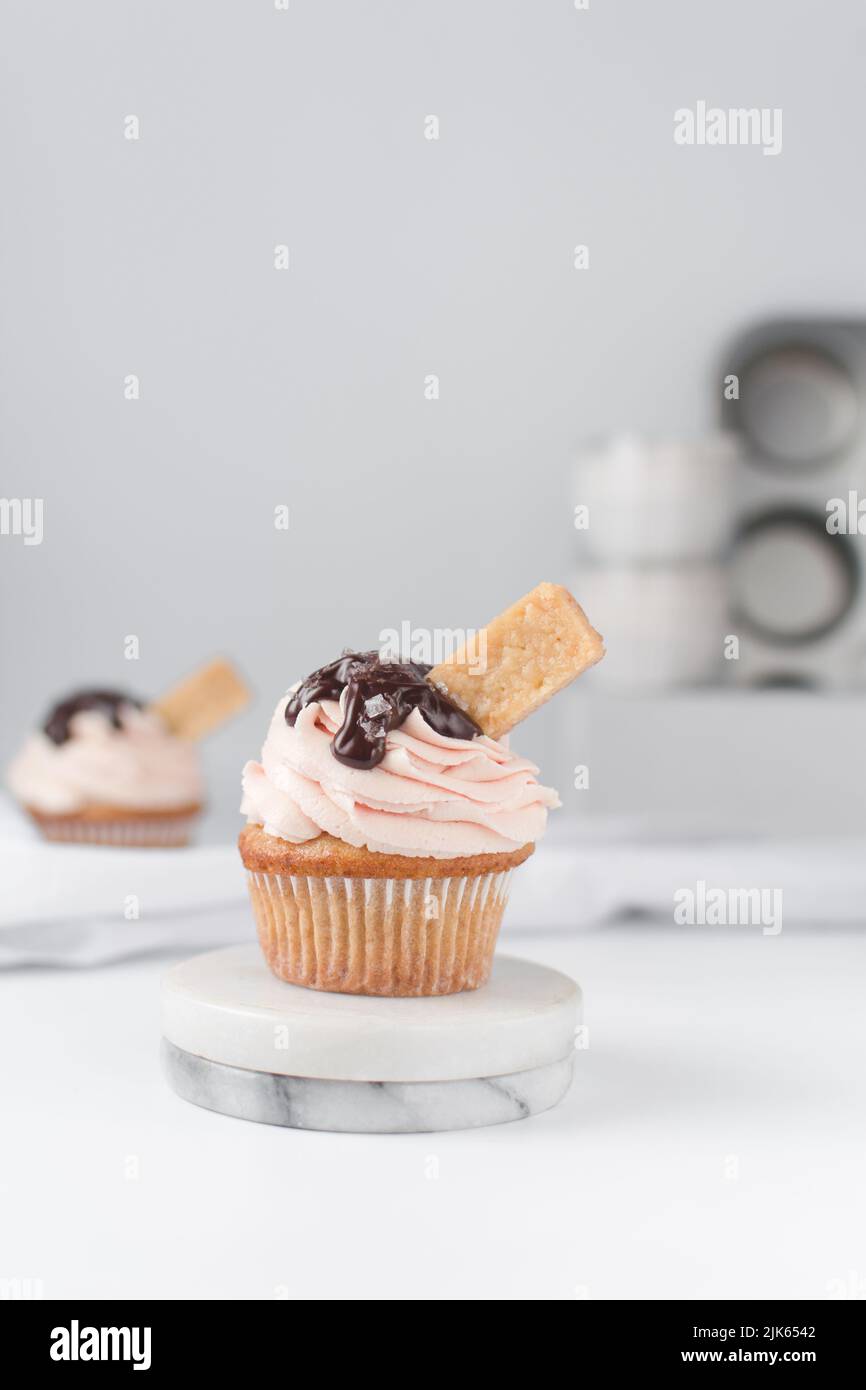 Single vanilla cupcake with a tall swirl of pink frosting, chocolate ...