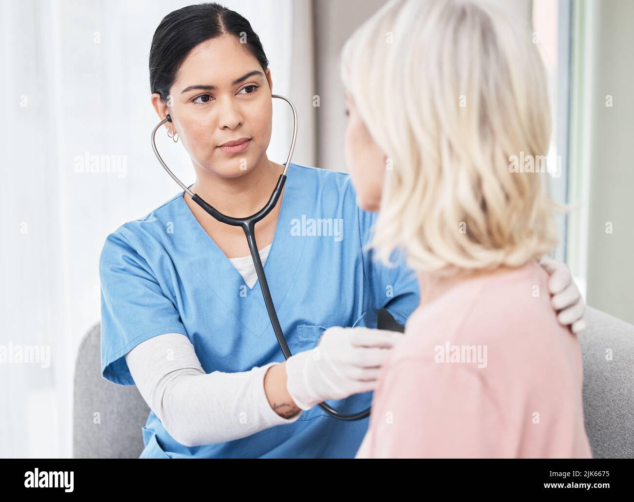 Take a deep breath for me. a female doctor examining a patient with a ...