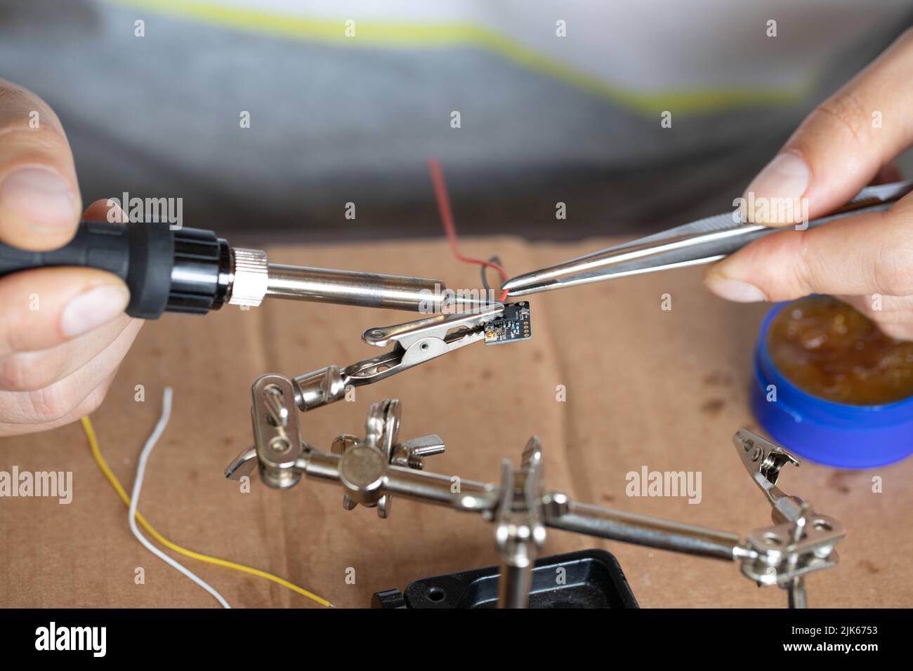 The hand holding the tin, a soldering iron solder the chip in place. a ...