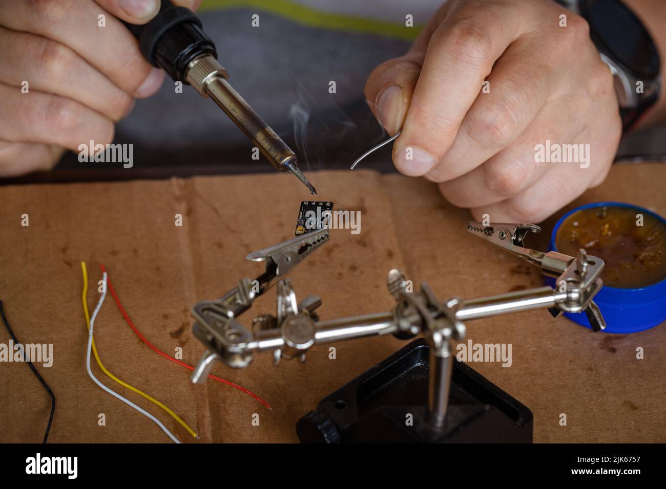 The hand holding the tin, a soldering iron solder the chip in place. a ...