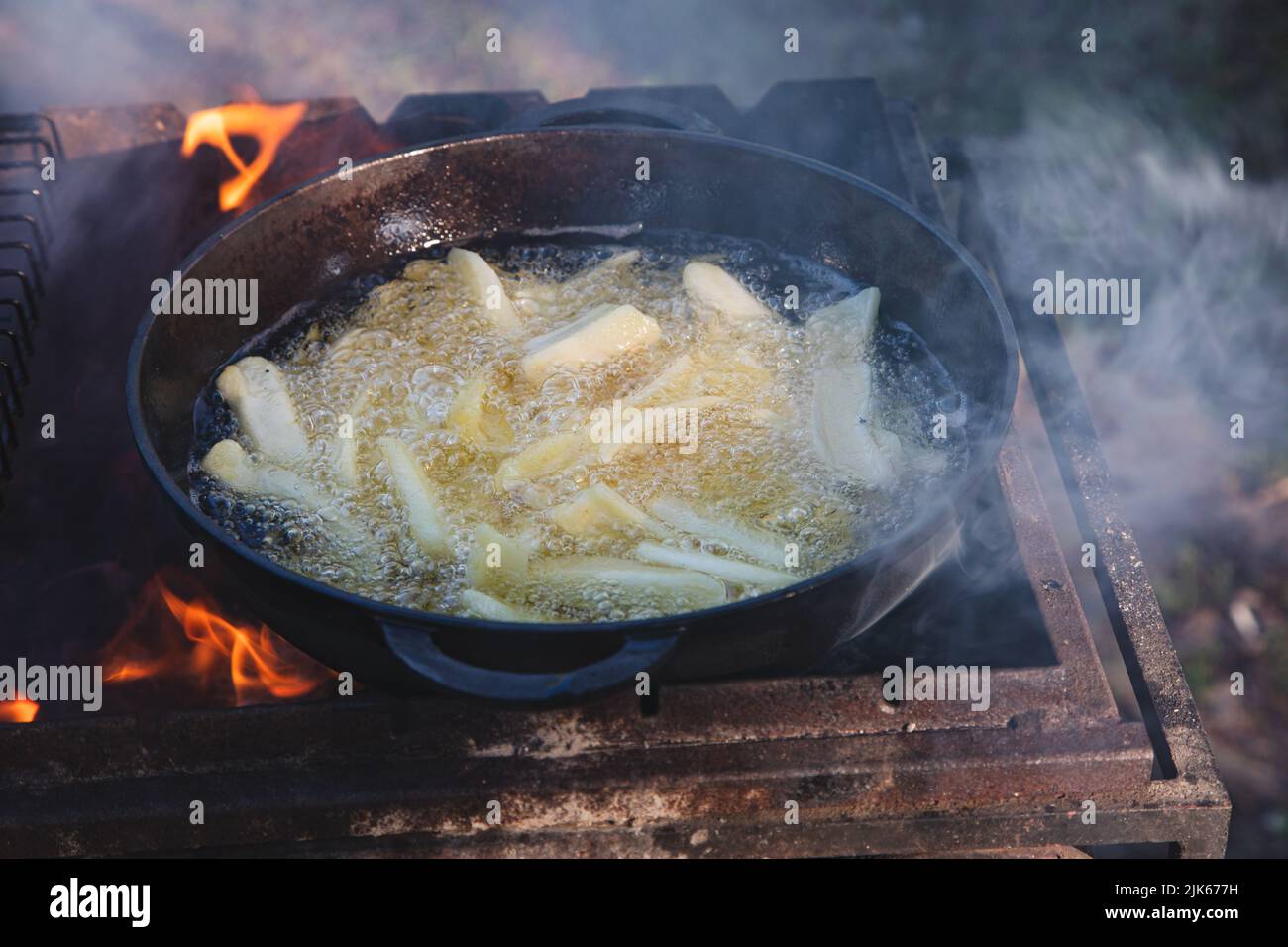 the process of cooking french fries on a fire in a cauldron. time for a ...