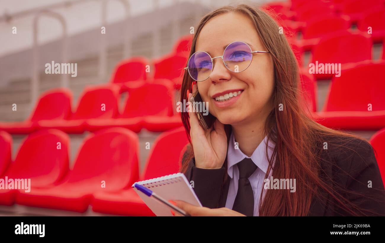 Female journalist speaking on smartphone, discussing competitions at ...