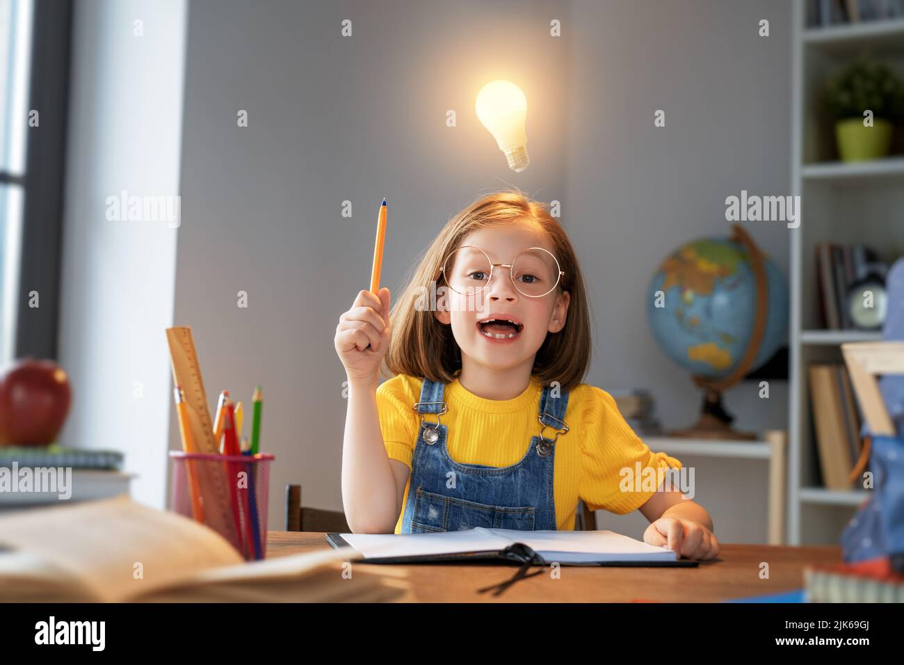 Back to school! Happy cute industrious child is sitting at a desk ...