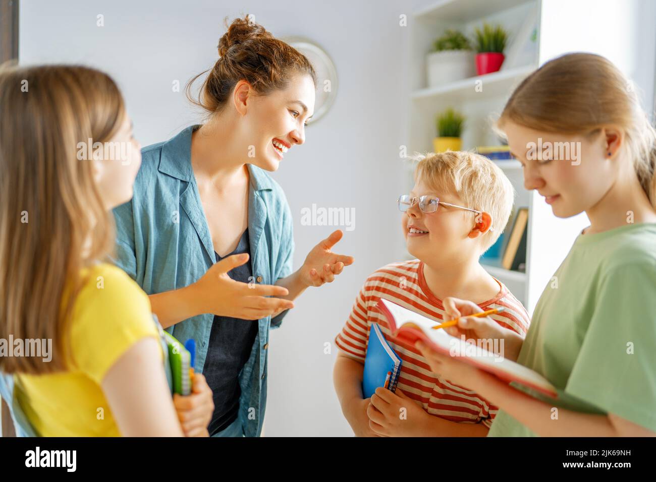 Happy kids and teacher at school. Woman and children are talking in the ...