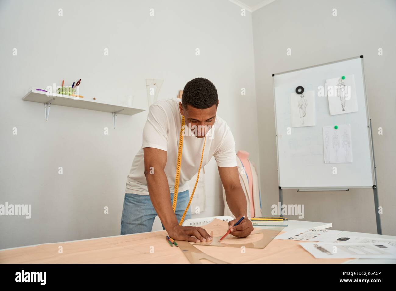 Happy male tailor making patterns on paper before sewing Stock Photo ...