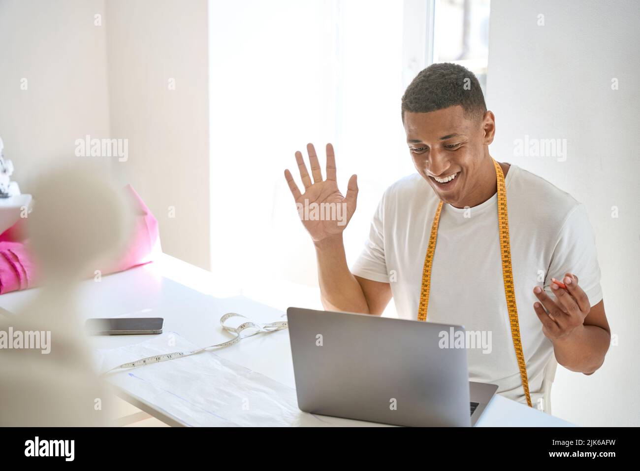 Merry man chatting online in fashion atelier Stock Photo - Alamy