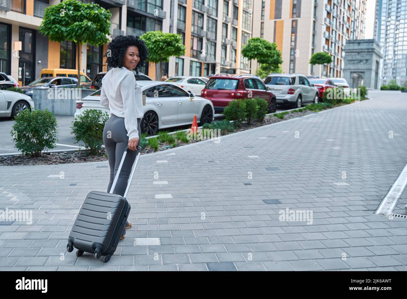 Pretty traveler women is walking through metropolis with small suitcase ...