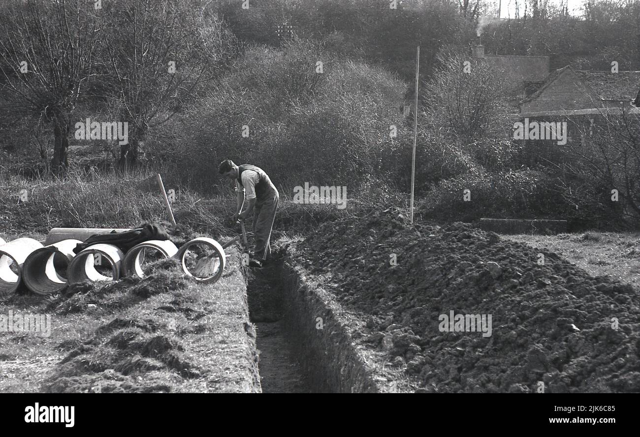 1960s, historical, outside in a rural field, a man at work, digging a ...