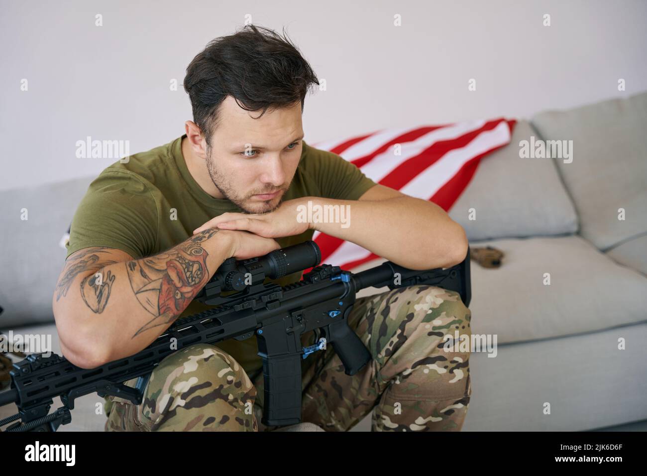 Soldier leaning on his rifle while waiting in room Stock Photo - Alamy